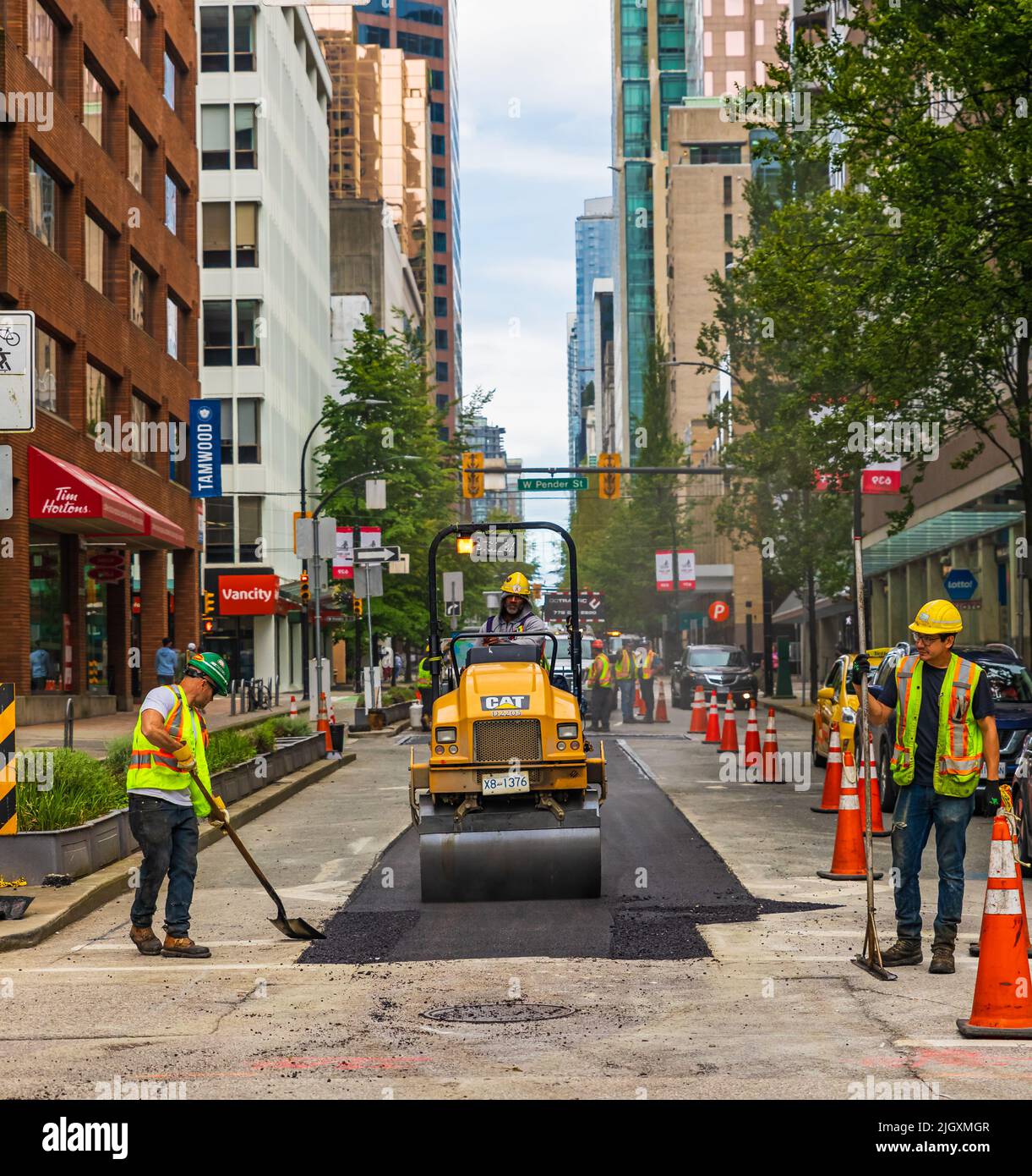 Team of workers put the hot asphalt on a road. Road construction ...