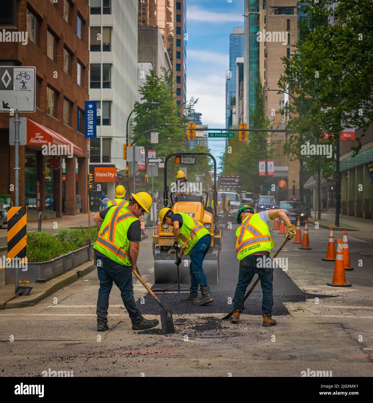 Team of workers put the hot asphalt on a road. Road construction ...