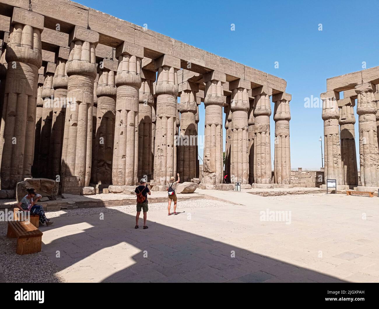 Tourists contemplating the ruins of an ancient egyptian temple with ...