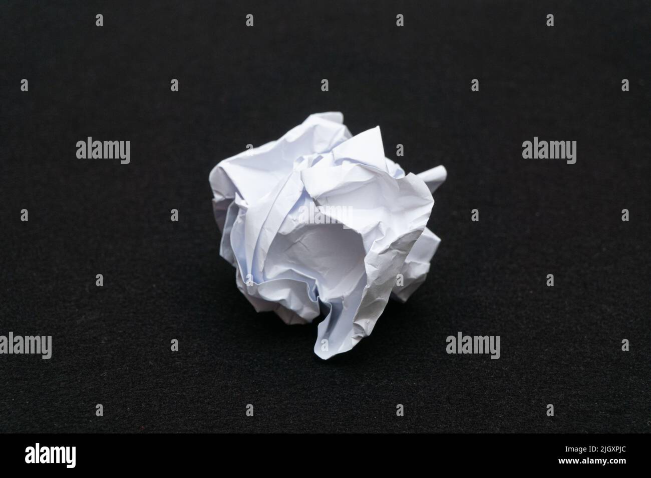 A mess of crumpled paper trash on a black background Stock Photo - Alamy