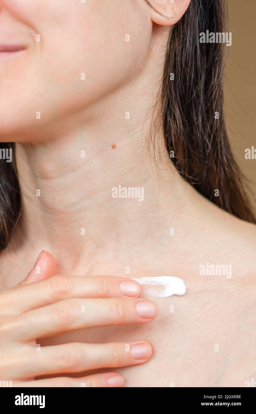 An unrecognizable woman applies a moisturizer to her collarbone. Body ...