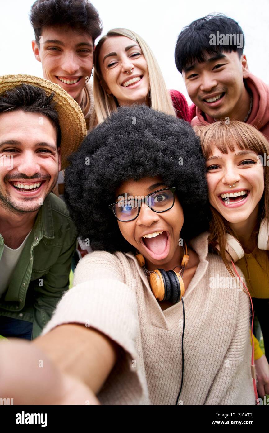 Vertical photo of Cheerful group of friends taking smiling selfie ...