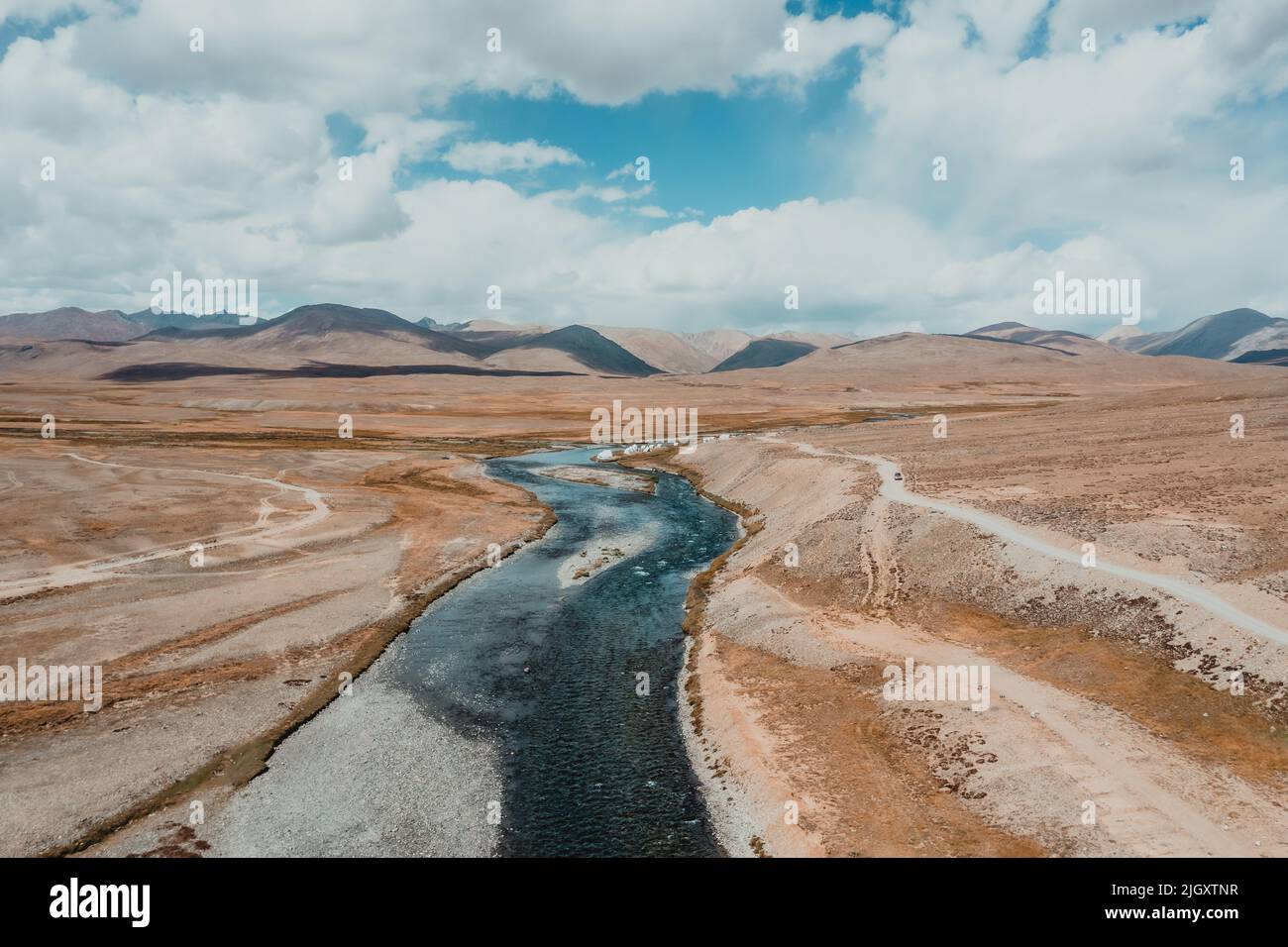 blue natural river flowing between dry desolate plateau with mountain ...