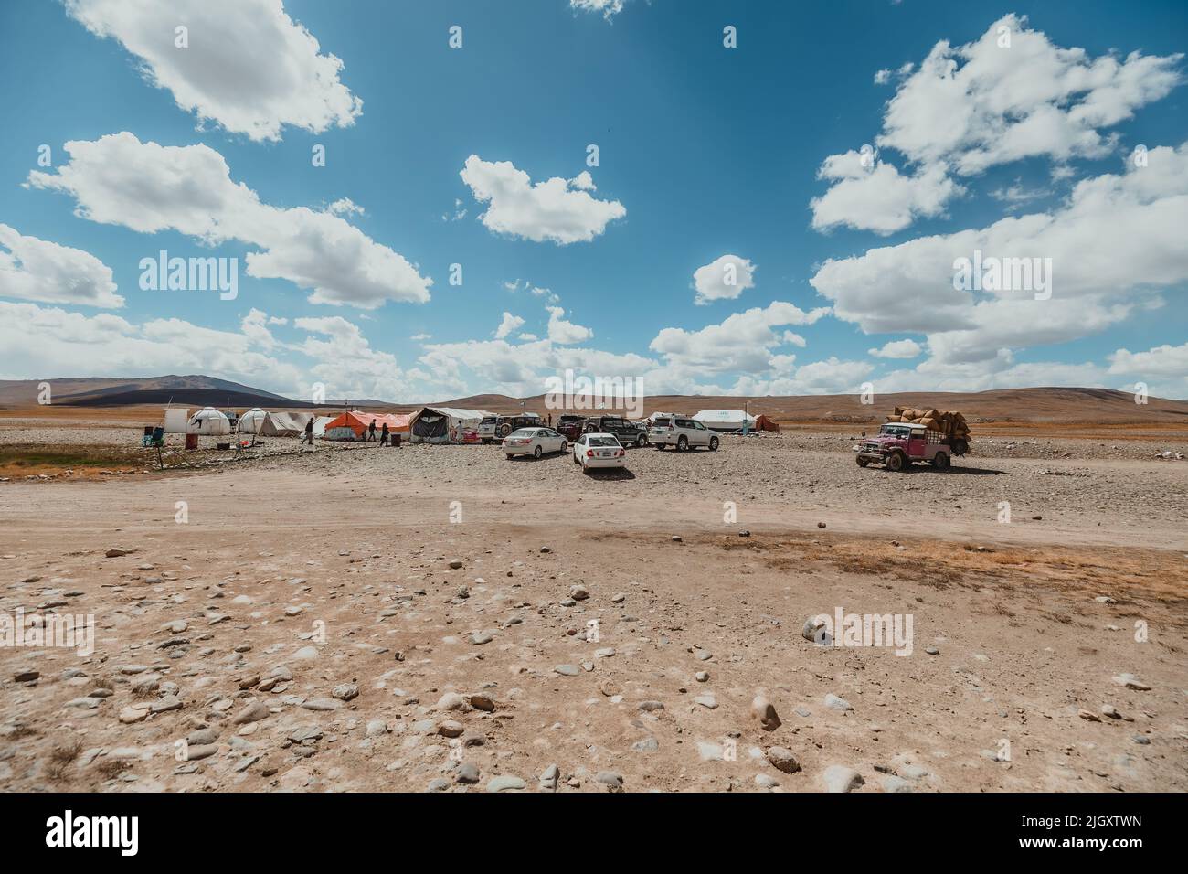 cars parked at a rest stop with tents in the desolate dry terrain of ...