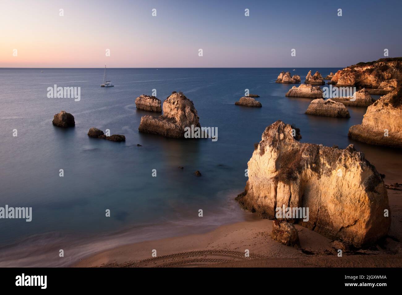 A scenic view of a rocky beach during sunset Stock Photo - Alamy