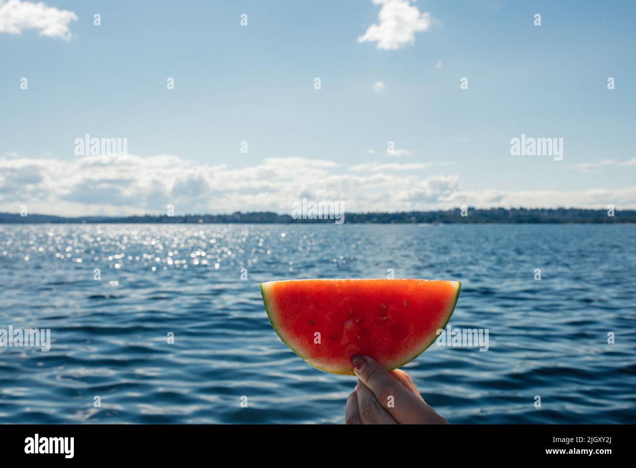 hand holding up watermelon semi moon, circle slice out on boat, lake ...