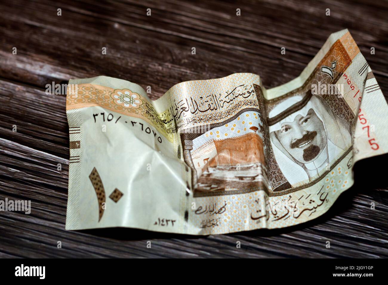 Crumpled Saudi Arabia money of 10 SAR ten riyals isolated on wooden ...