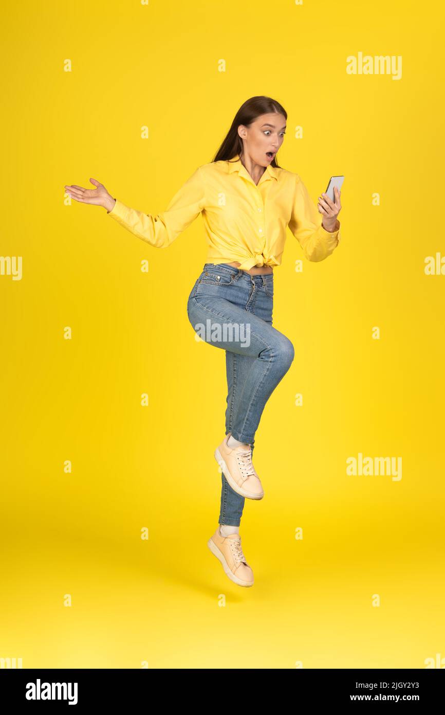 Shocked Lady Holding Smartphone Jumping Posing Over Yellow Background ...