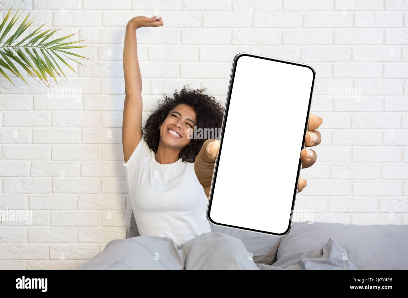 Happy Black Female Holding Big Blank Smartphone And Stretching In Bed Stock Photo - Alamy