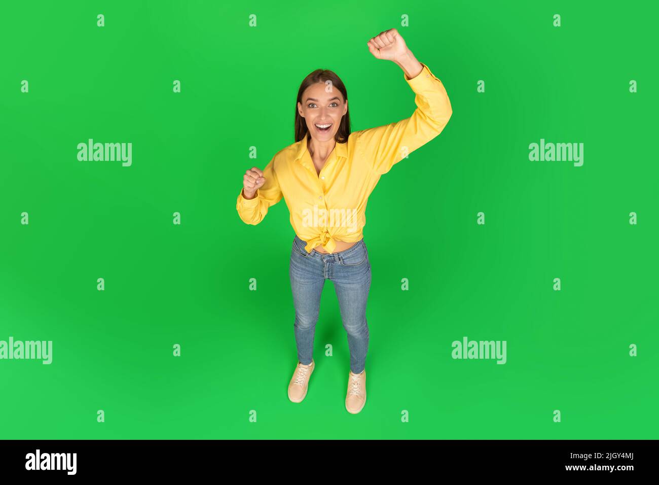 Cheerful Woman Shaking Fist Smiling To Camera Over Green Background ...