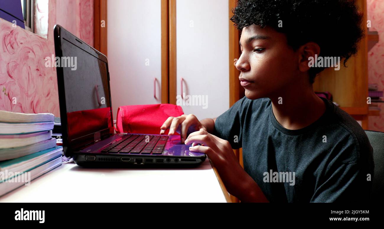 Child sitting down at desk opens laptop and turns computer on preparing ...