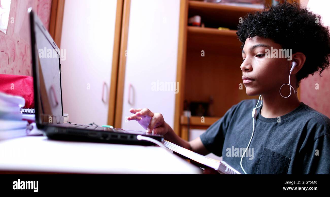 Child sitting down at desk opens laptop and turns computer on preparing ...