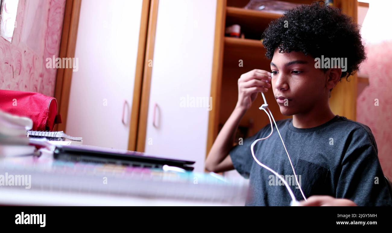 Child sitting down at desk opens laptop and turns computer on preparing ...