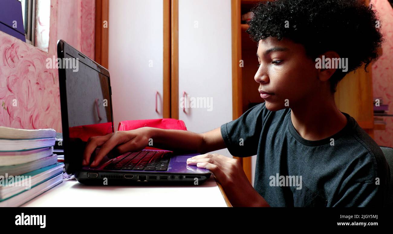 Child sitting down at desk opens laptop and turns computer on preparing ...