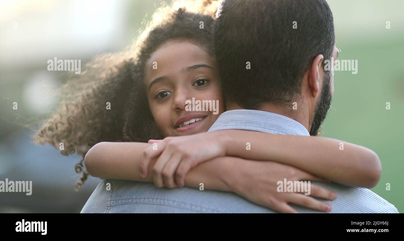 Cute little girl hugging father. Mixed race kid embraces dad outside in ...