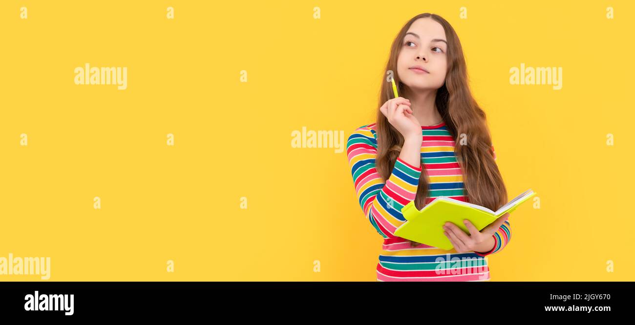 Thoughtful kid think over school essay holding pen and copybook yellow ...