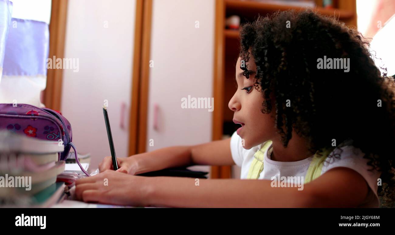 Diverse little girl studying at home. Black ethnicity child doing ...