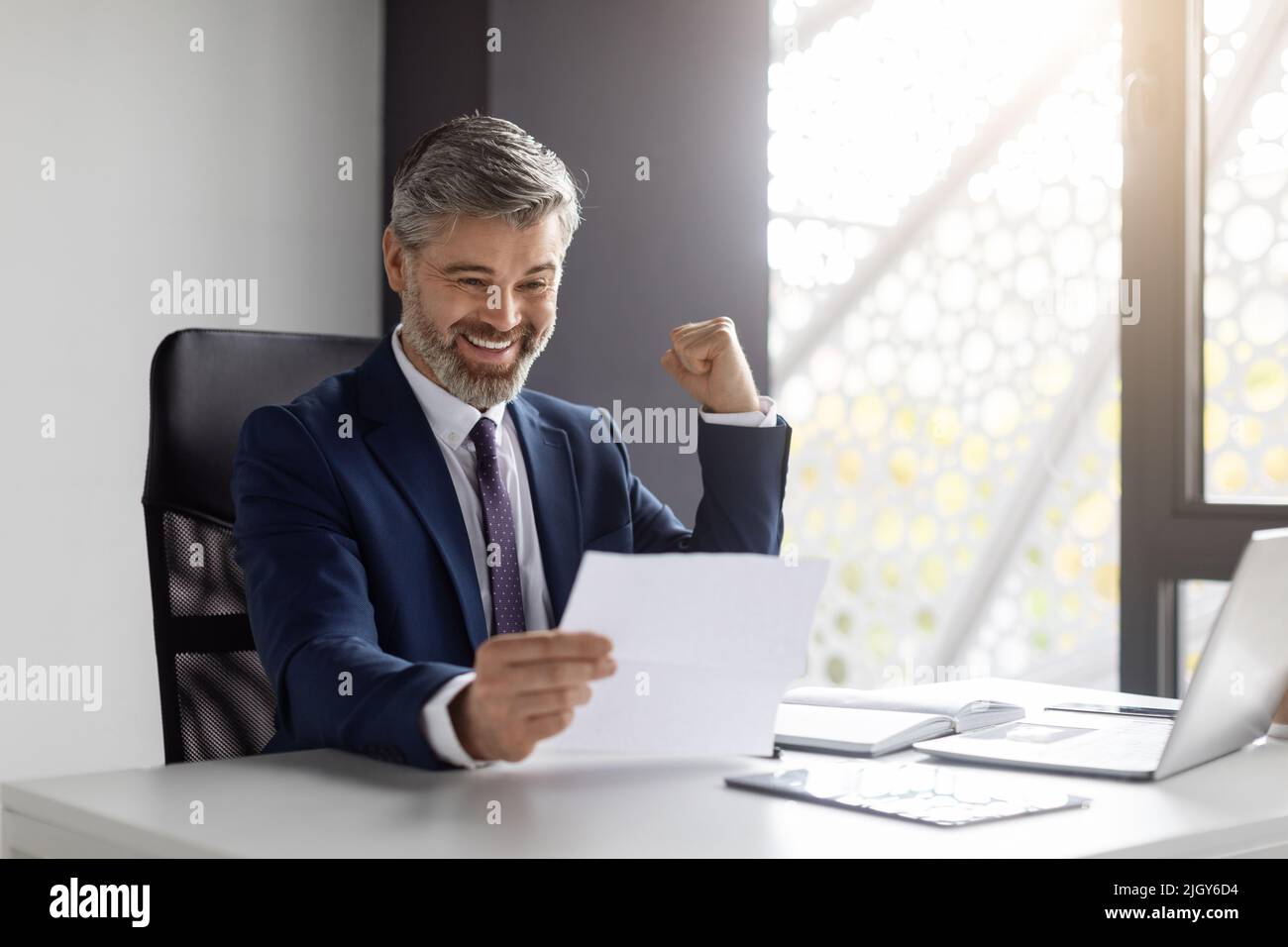 Businessman celebrating success reading documents hi-res stock ...