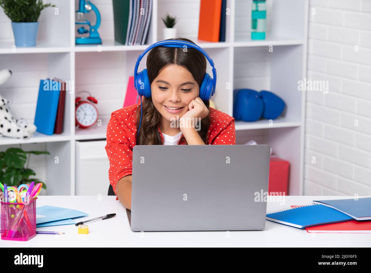 A young school girl student with wireless headphones sitting at the ...