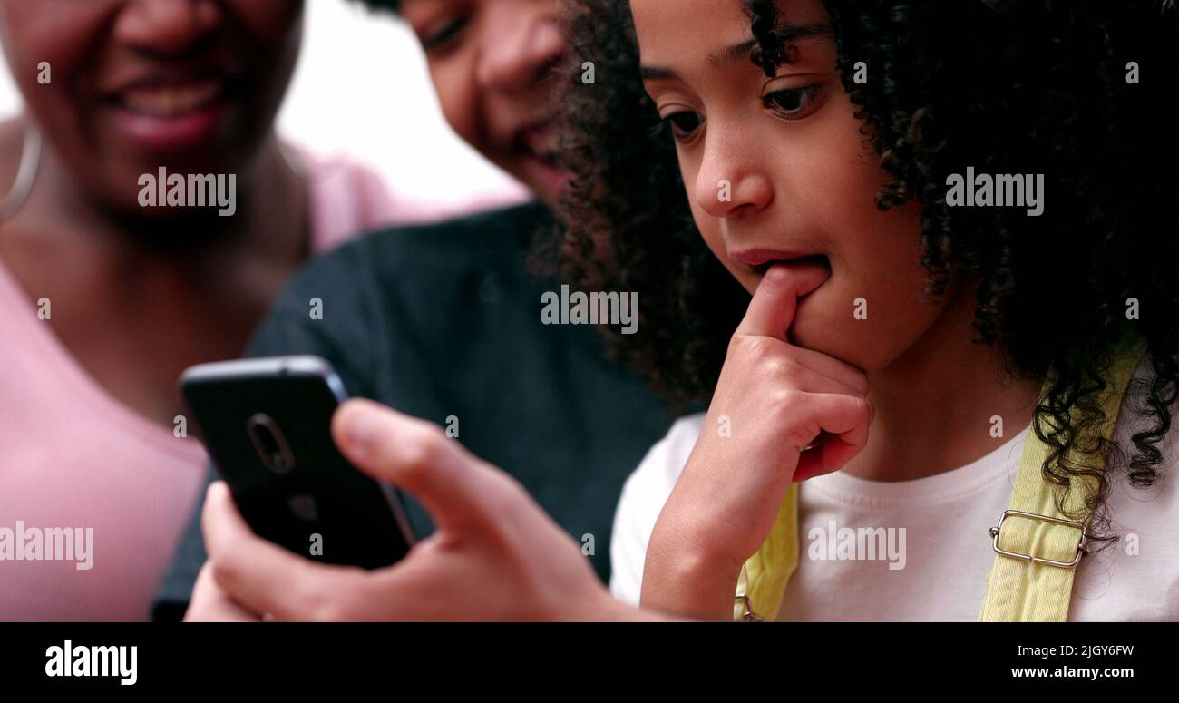 Family laughing and smiling together using phone. Authentic real life ...