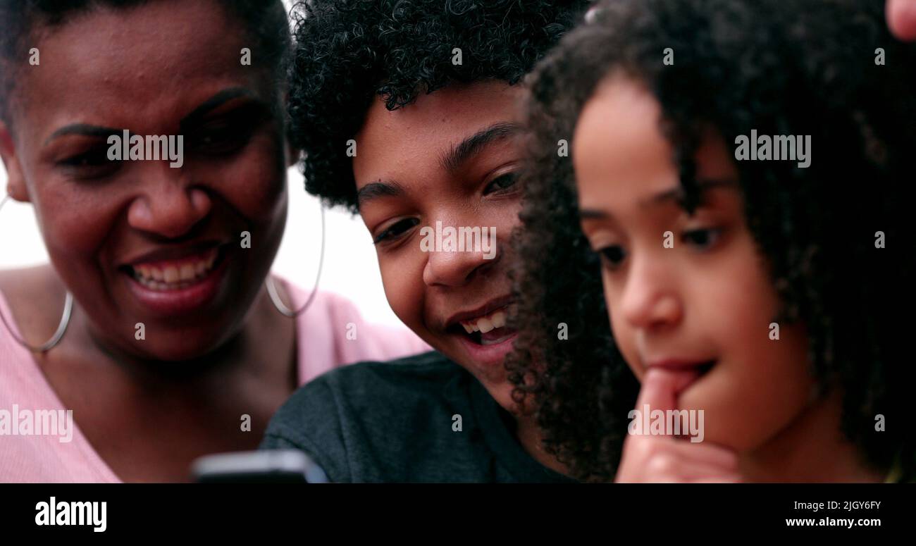 Family laughing and smiling together using phone. Authentic real life ...