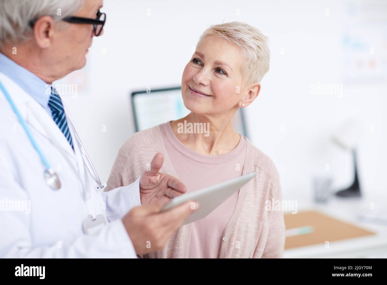 Smiling healthy senior female patient with short hair listening to ...