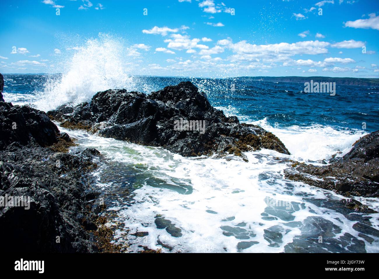 A view of a sea or ocean shore with waves washing the wet rocks under ...