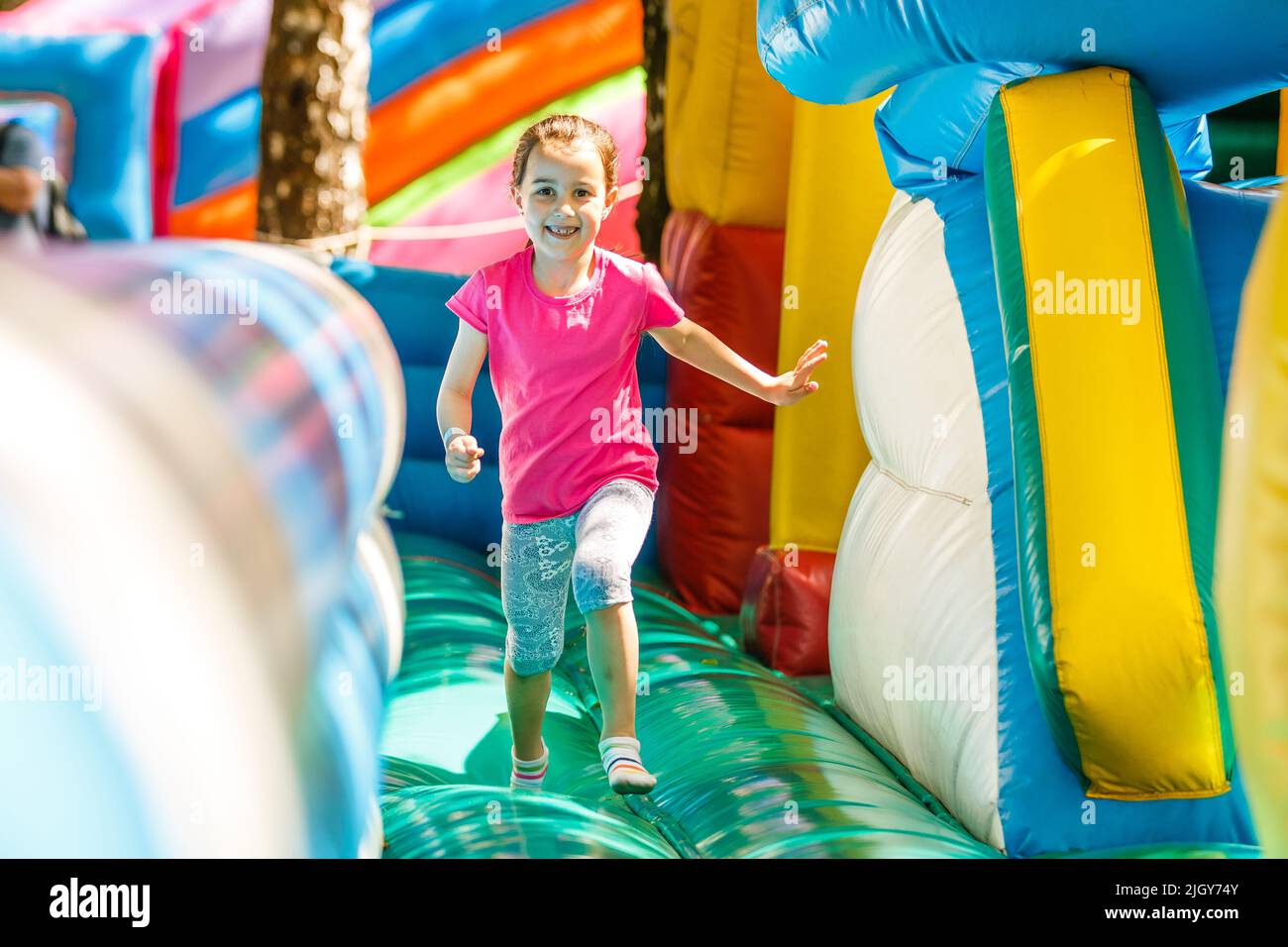 Happy little girl having lots of fun on a jumping castle during sliding ...