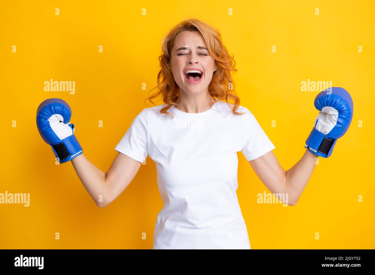 Winner female boxer with her hands raised excited. Isolated on yellow ...