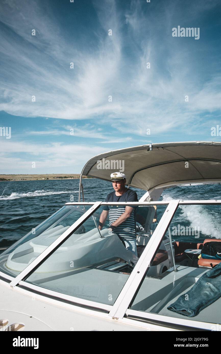 the captain of the yacht at the helm controls the boat on the water ...