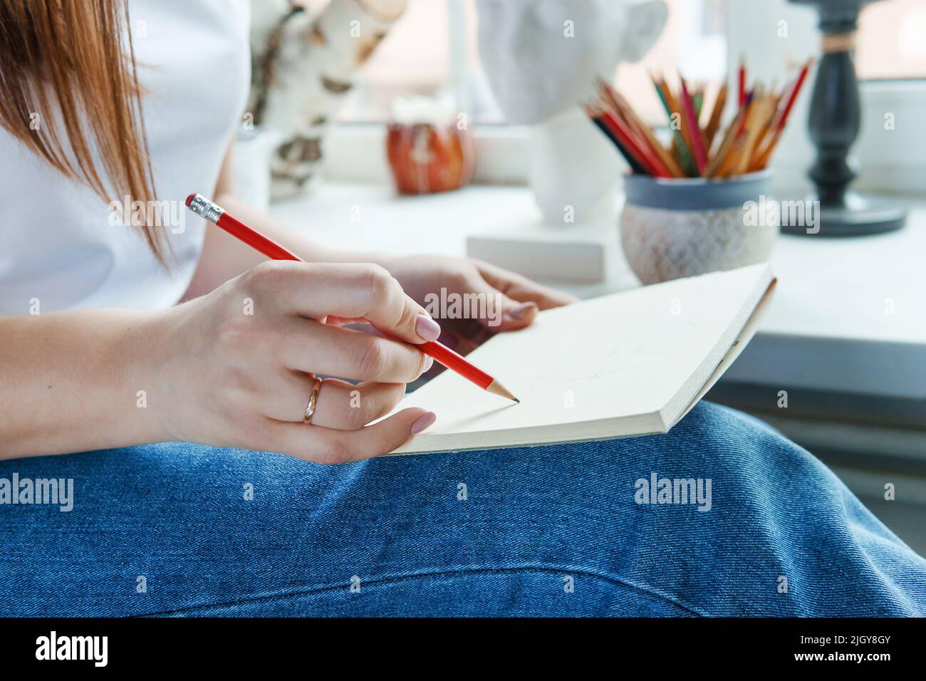 A pencil in a woman's hands. Drawing on sheet of paper with a simple ...