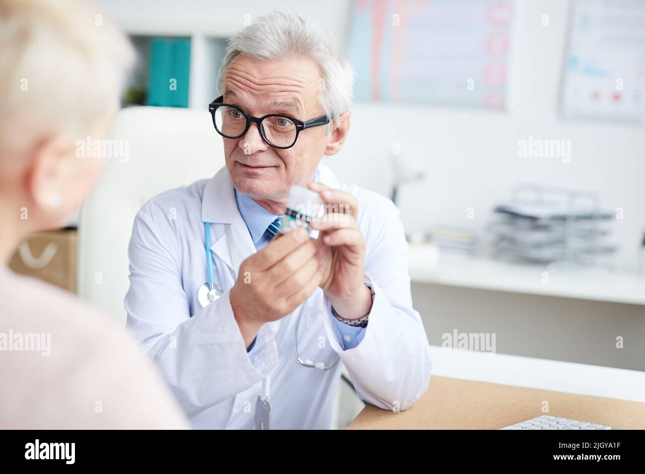 Content senior physician in eyeglasses frowning forehead while ...