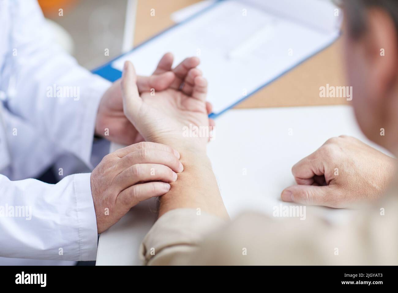 Close-up of unrecognizable male doctor in white coat sitting at table ...