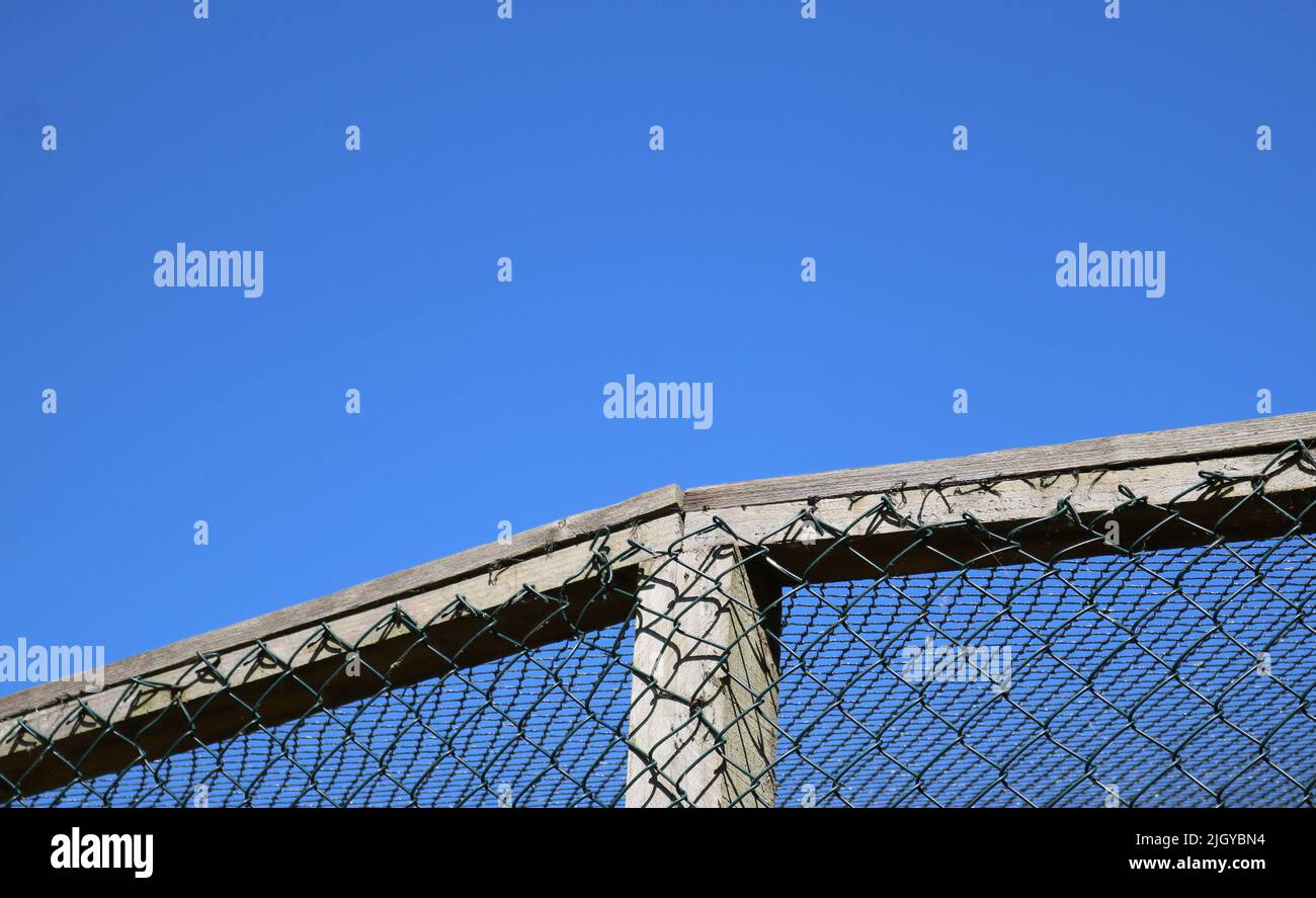 Enclosure background showing netted cage against deep blue sky with ...