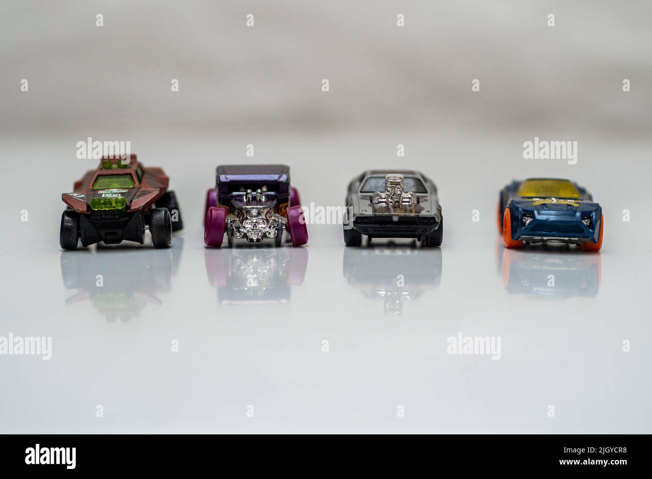 Four Hot Wheels die-cast miniature cars on a white surface Stock Photo ...