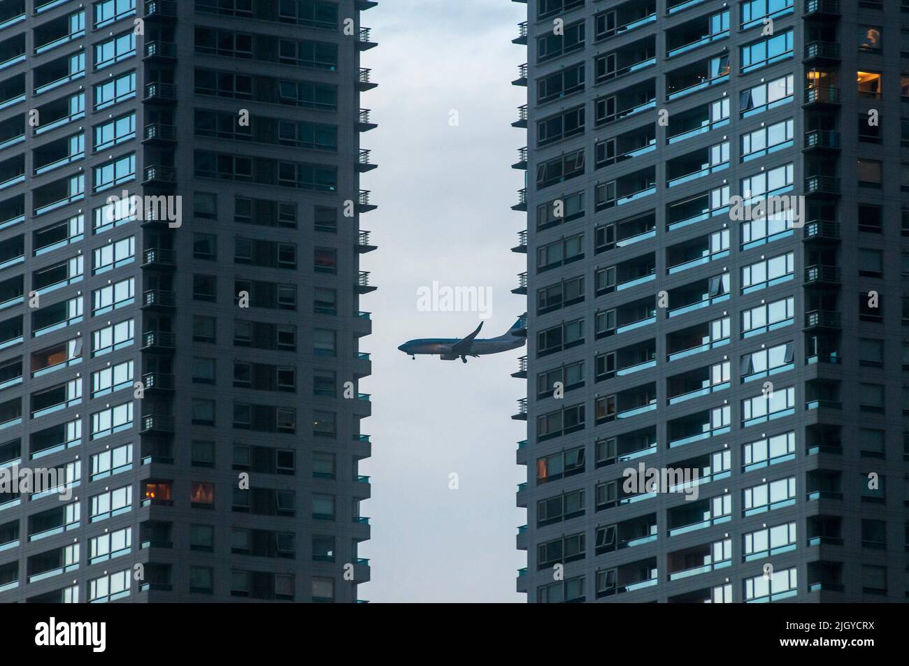 A plane in flight seen between two buildings in the evening Stock Photo ...