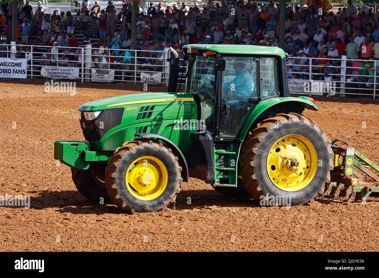 rodeo scene, man on green tractor, grooming arena dirt, job, motion ...