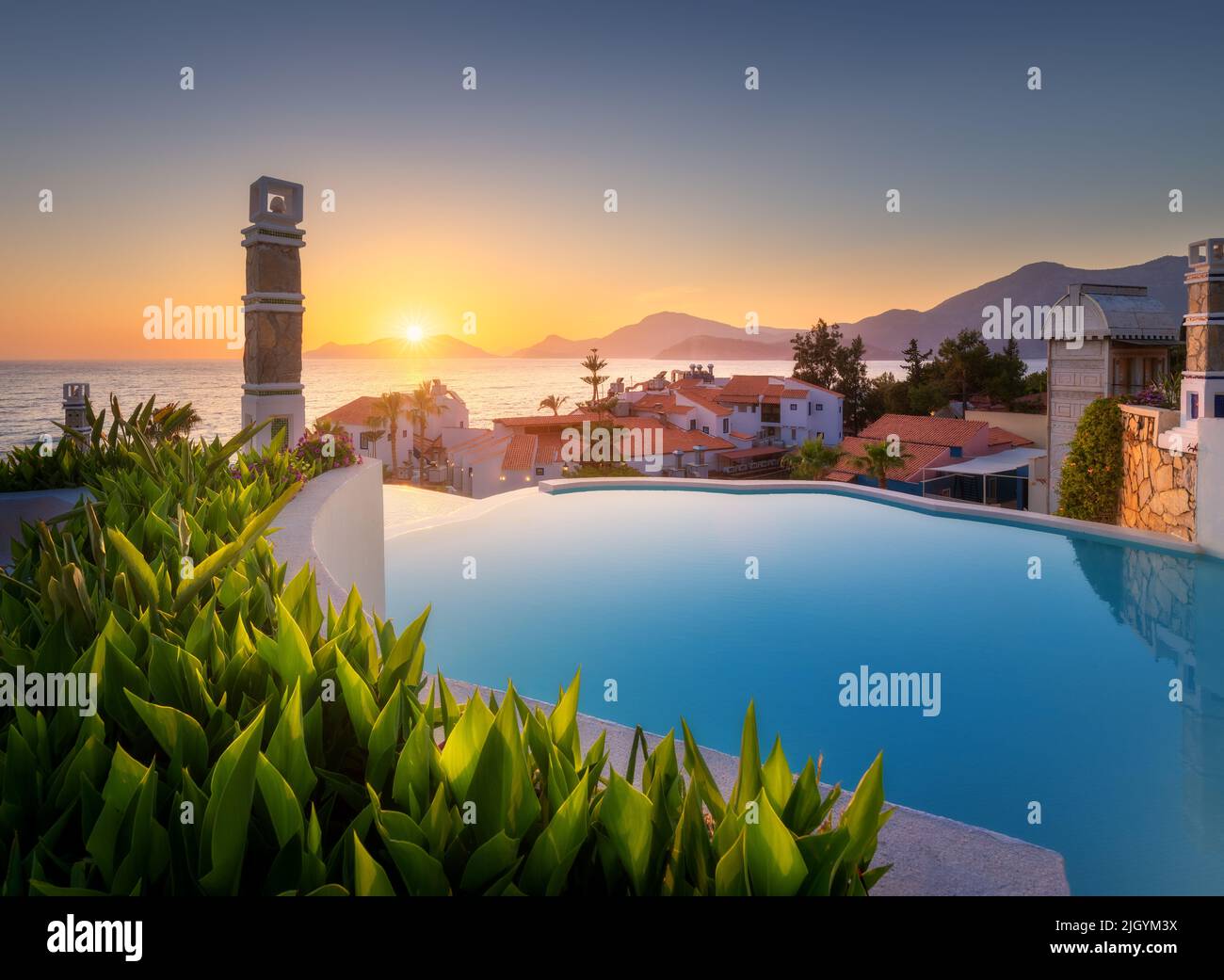 Beautiful swimming pool, green bush and orange roofs at sunset Stock ...