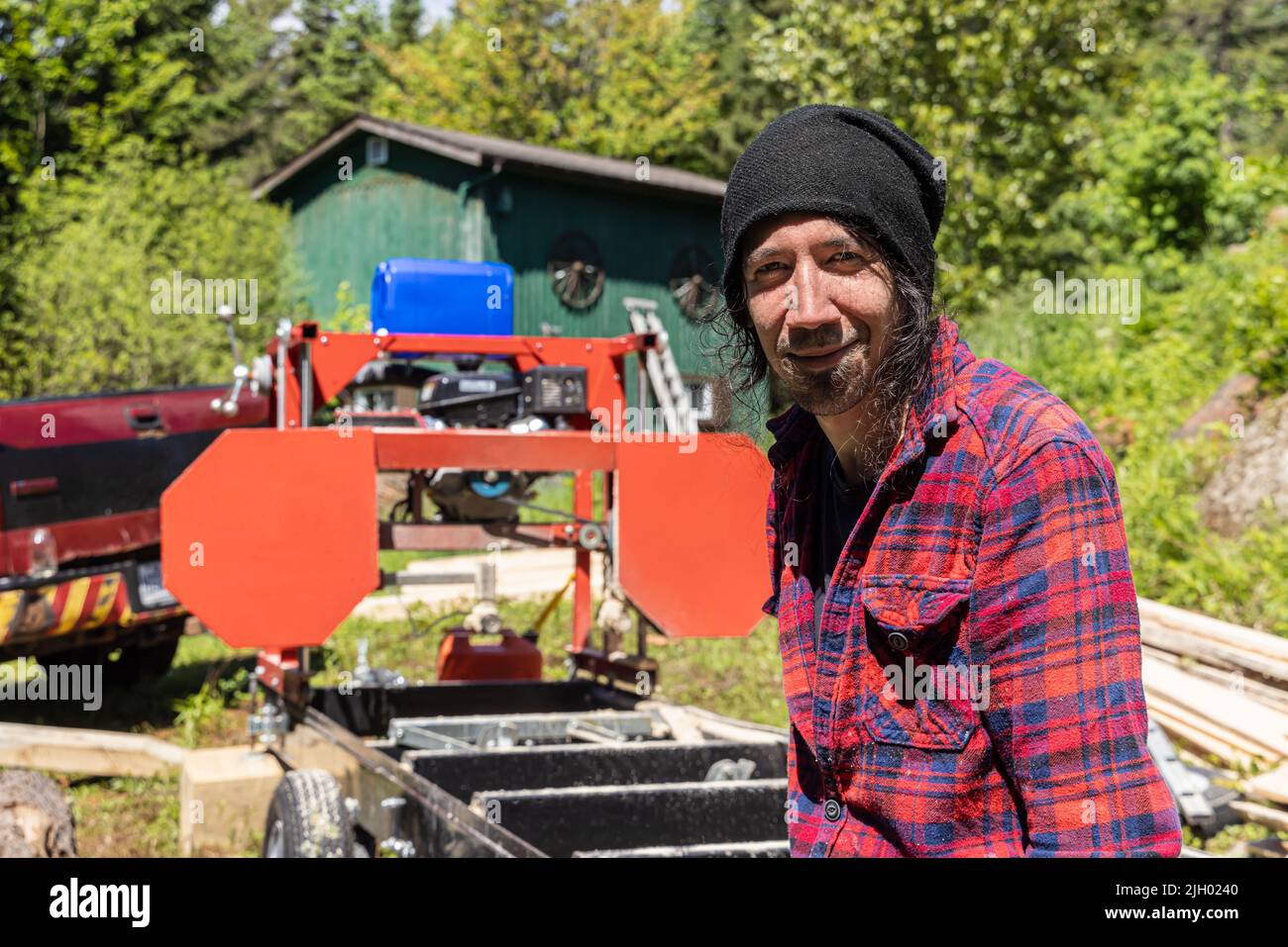 Close up portrait of a male lumberjack in mid thirties at work outdoors ...