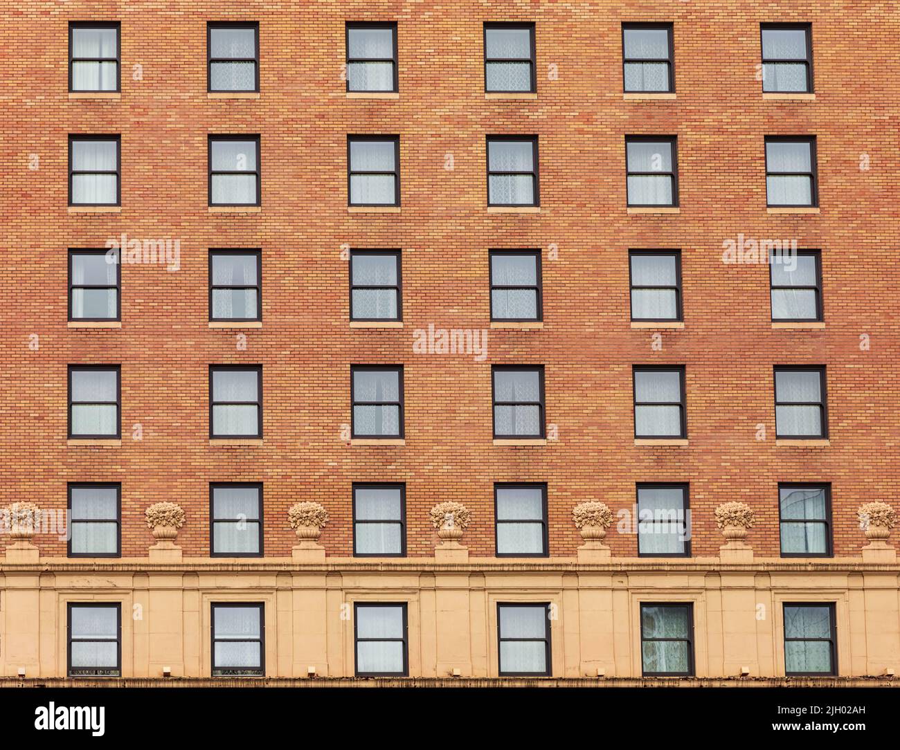 Many windows in row on facade of urban apartment building. Brick ...