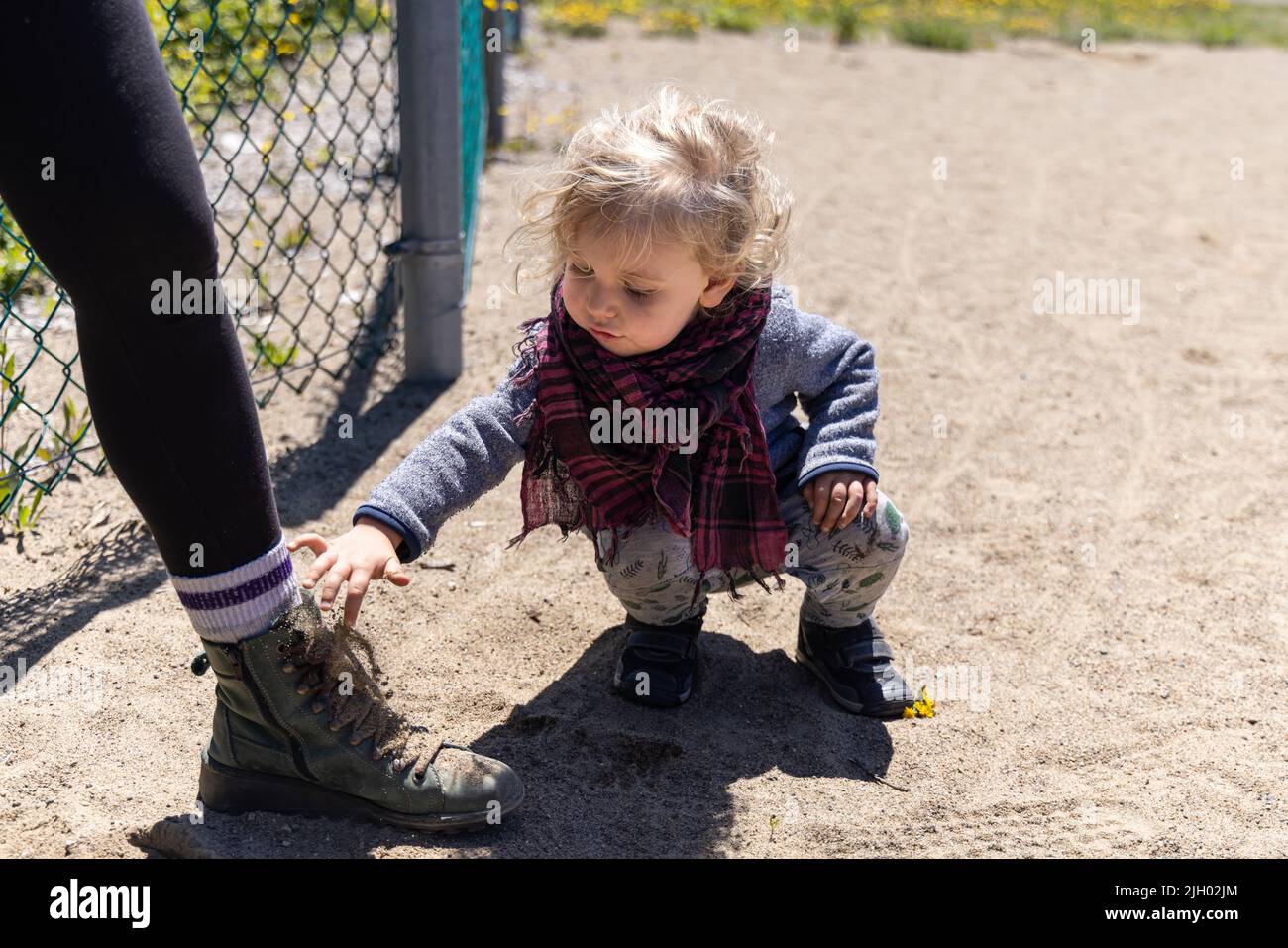 Close up shot of a crouching two year curious boy, wearing red scarf ...