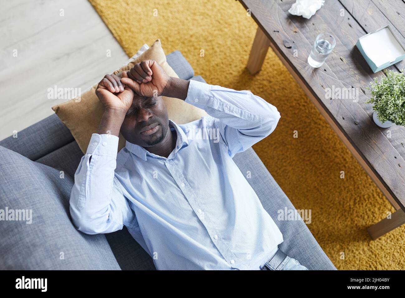 Directly above view of disturbed young Black man with closed eyes lying ...