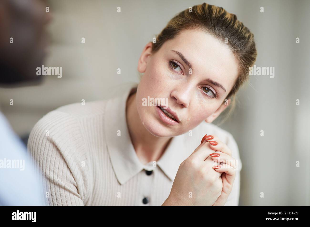 Crying young woman with rears on face sharing her pain with therapist ...