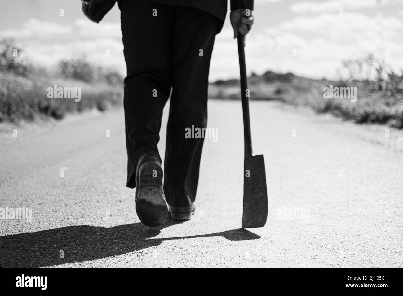 A grayscale shot of a man's legs with an axe on the road Stock Photo ...