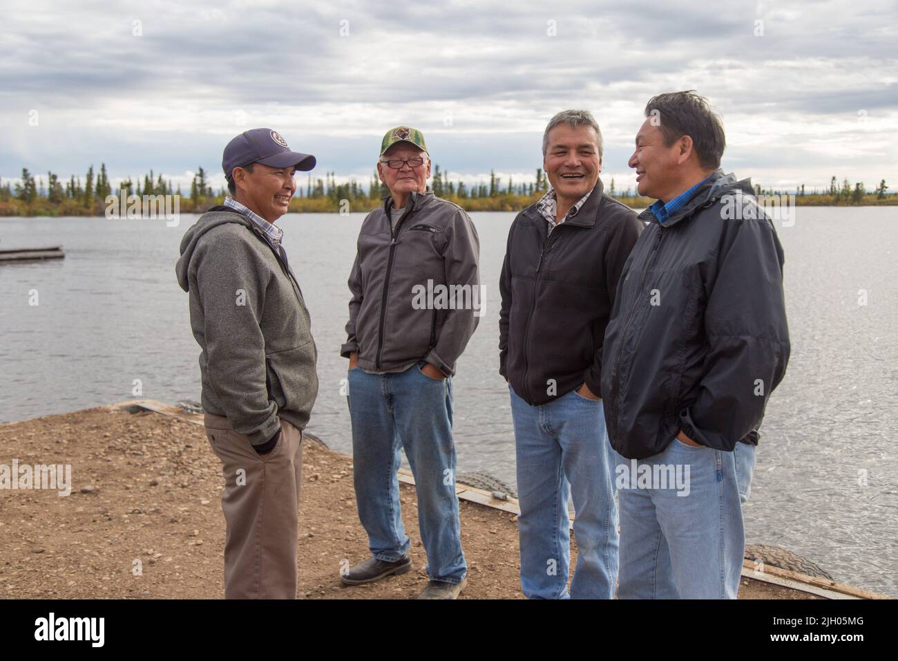 Indigenous Dene men in conversation outdoors by Great Bear Lake, in the ...