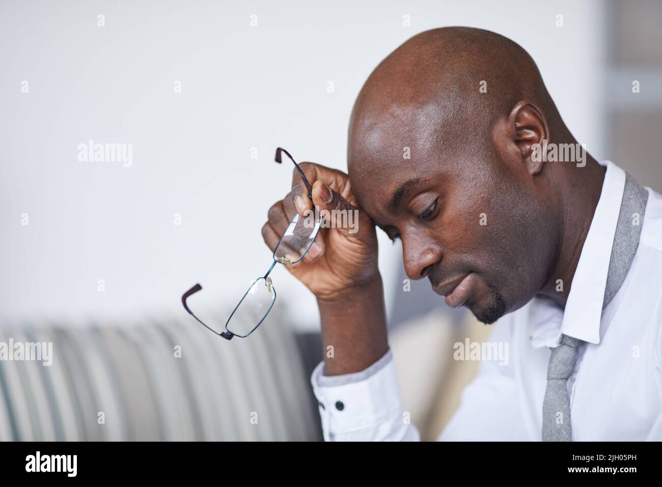 Serious confused young black businessman with bald hairstyle leaning ...