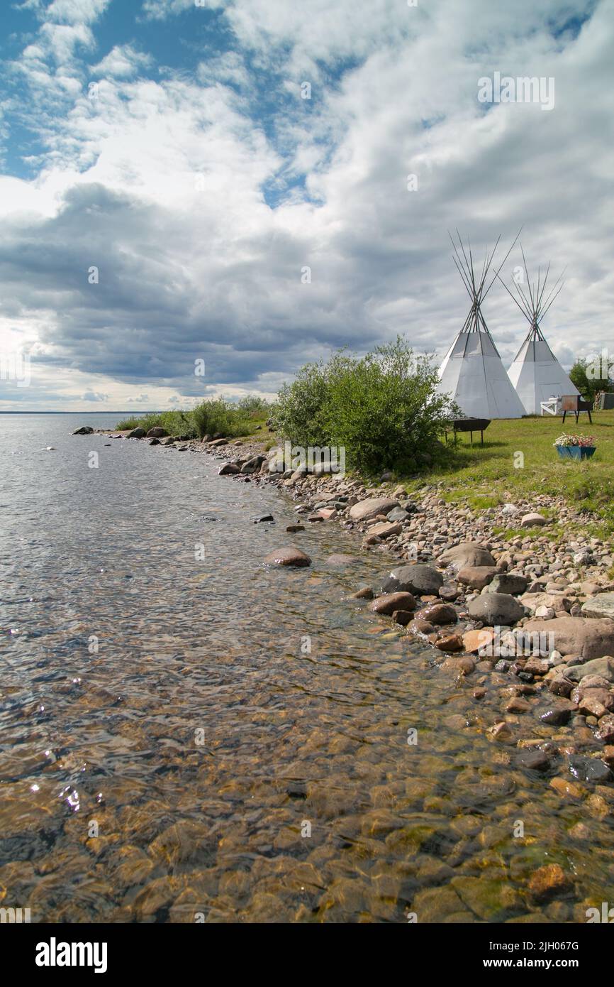 Shoreline of Great Bear Lake in summer, with teepees in the distance ...