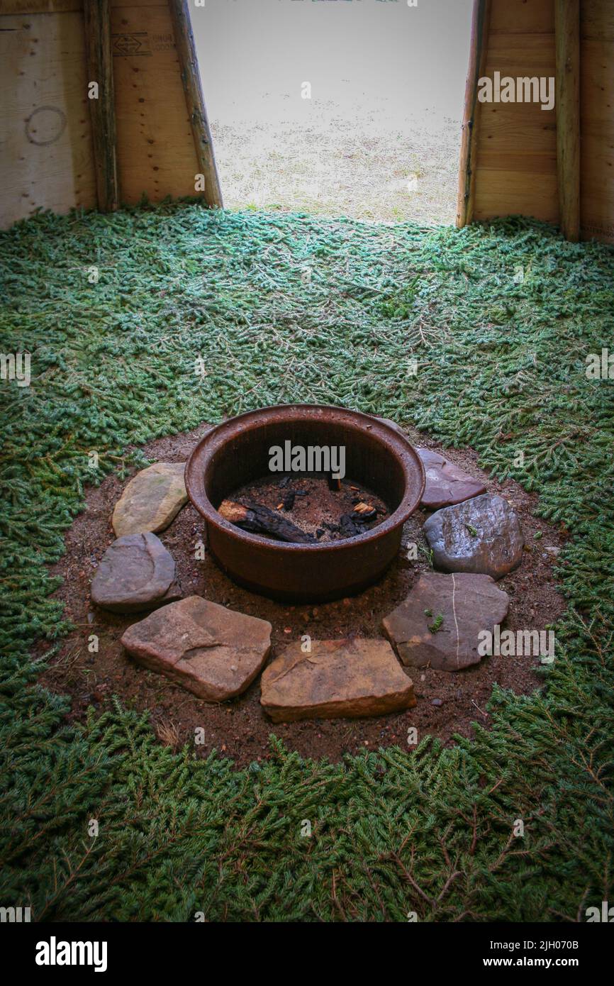 Fire pit inside a teepee, surrounded by spruce tree boughs, in northern ...