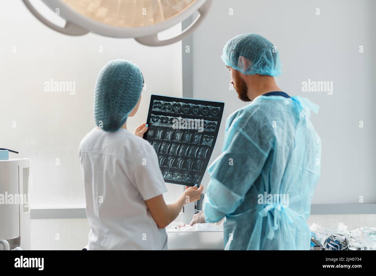 Doctor and nurse in uniform look and discuss an X-ray or MRI scan of ...