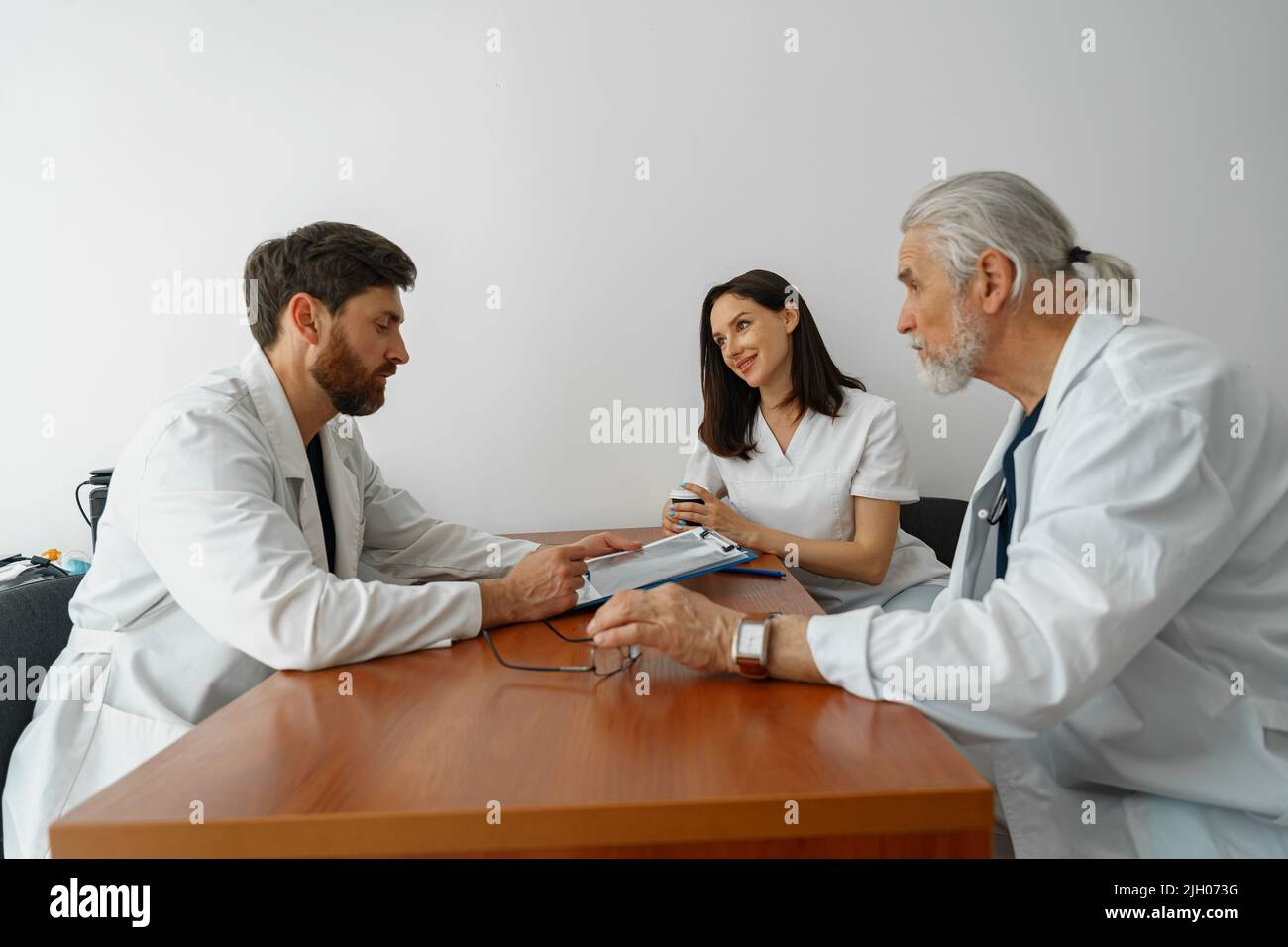 Group of doctors sitting at meeting table in conference room during ...